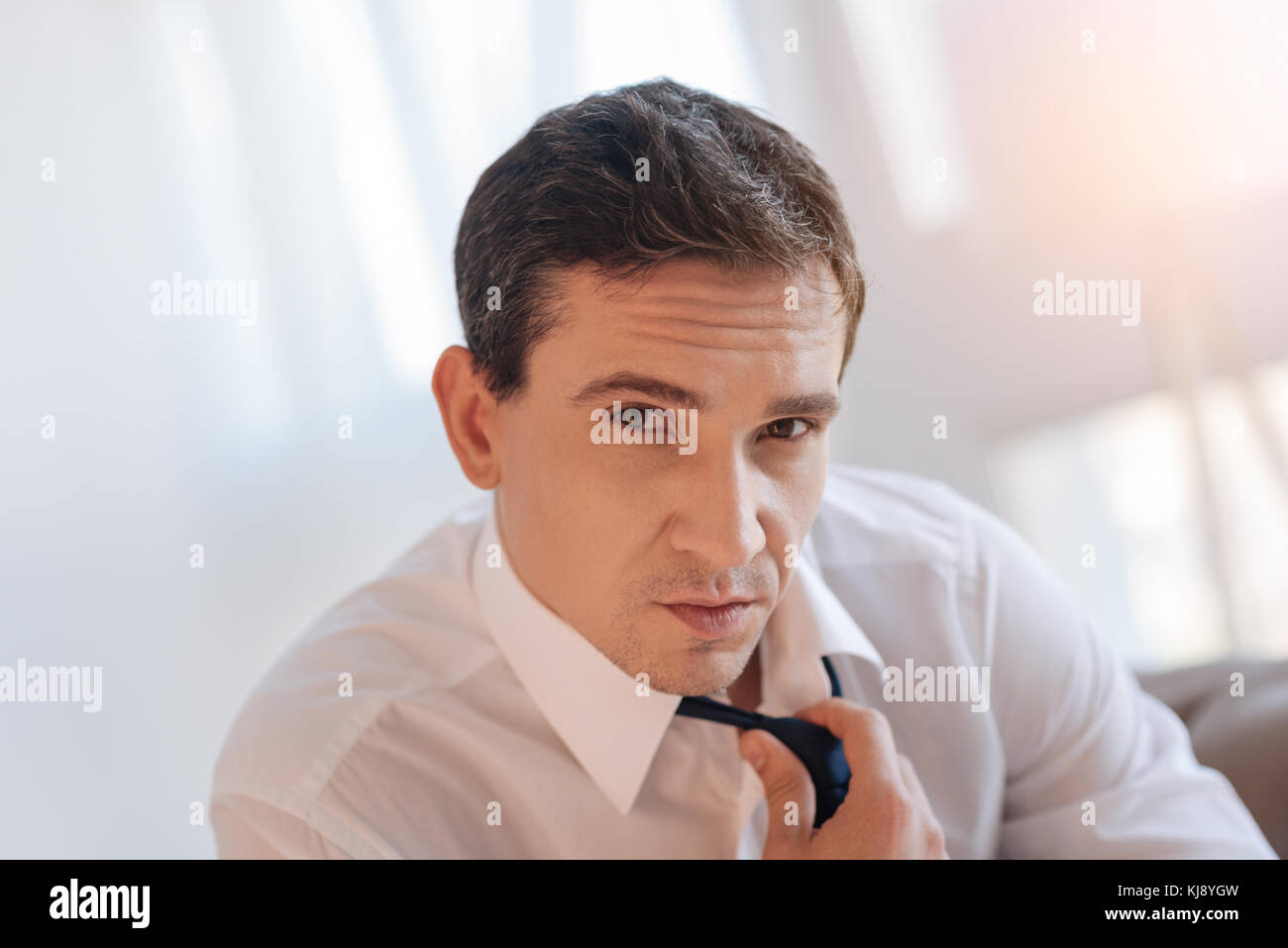 Clever professional worker looking confident while touching his tie ...