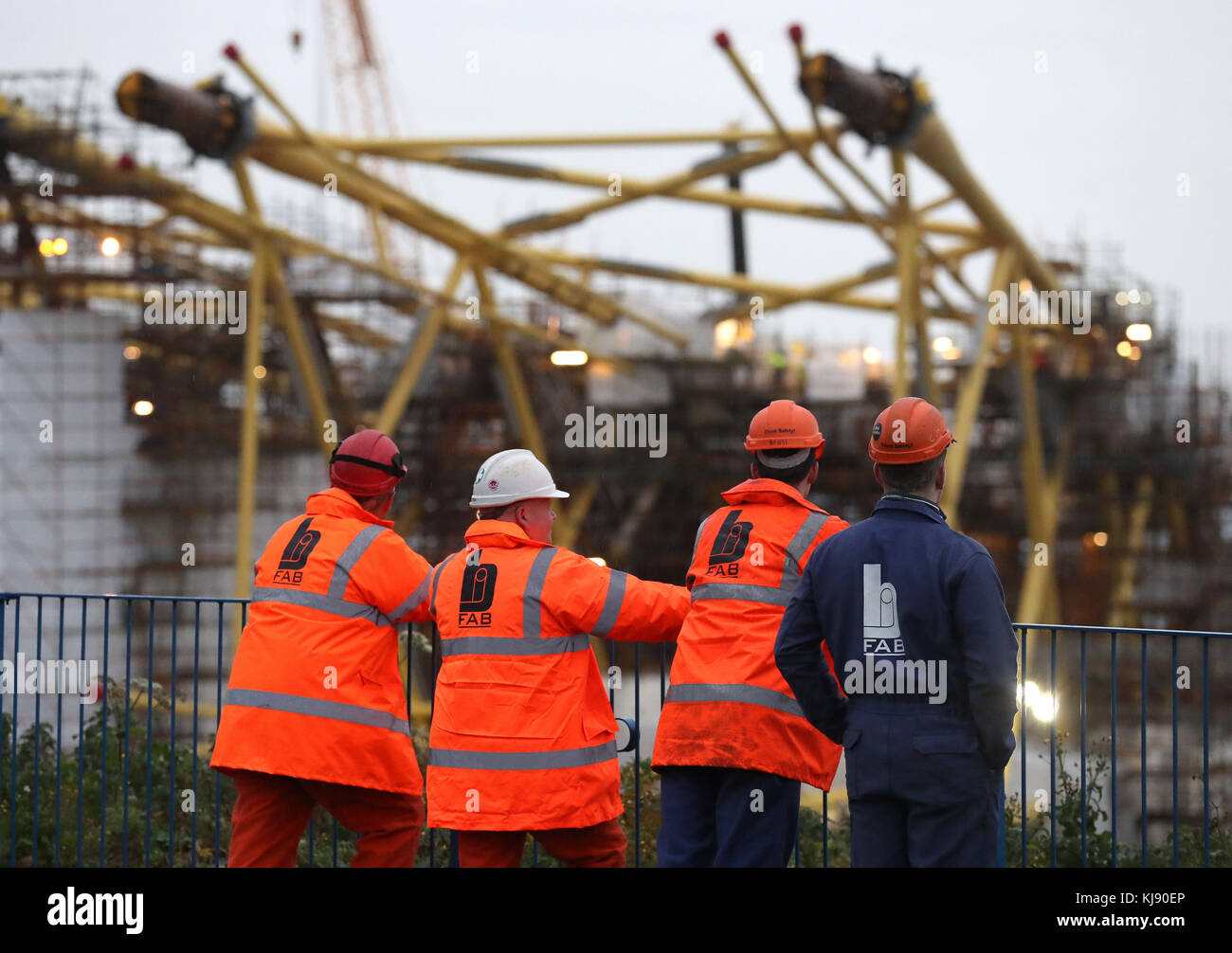 Work continues on wind turbine jackets as workers look from a viewing ...