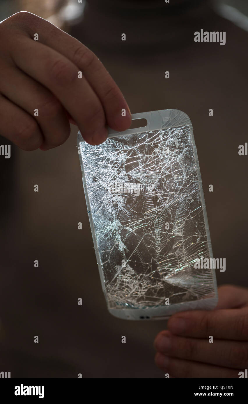 Hands holding a broken screen of smartphon. Backlight authentic light ...