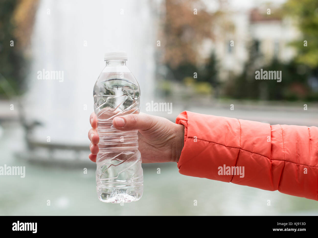 Bottle of water. Hand hold bottle mineral water in front of fountain ...