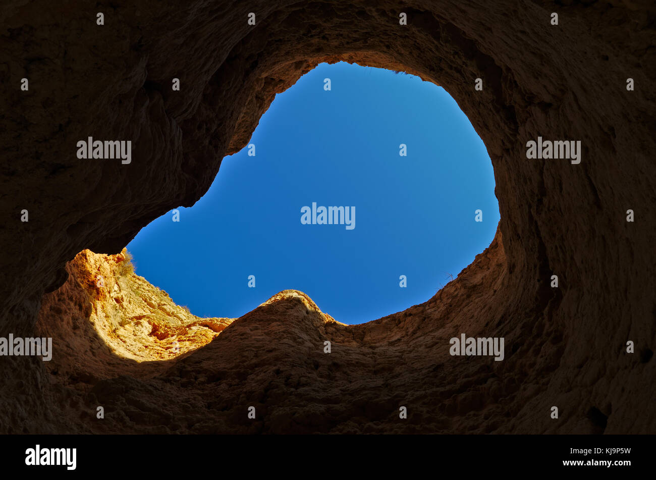 Looking to the sky through a cliff hole in Algarve, Portugal Stock ...