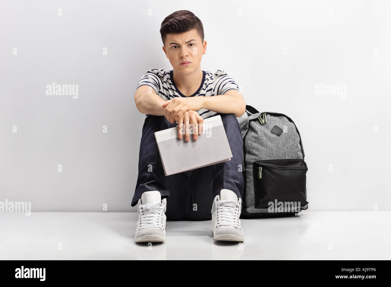 Sad teen student sitting on the floor and leaning against a wall Stock ...