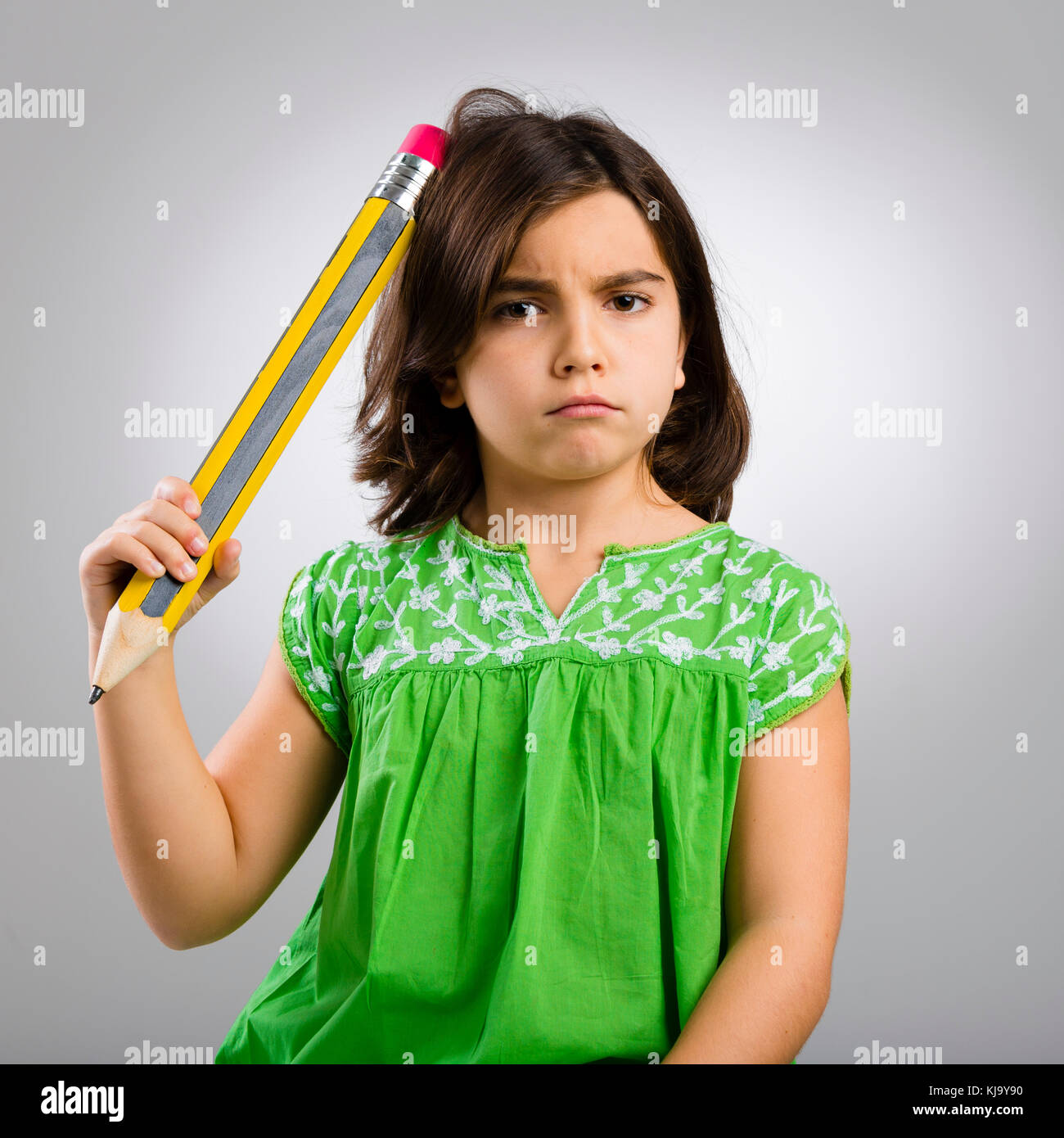 Studio portrait of a little girl thinking and scratching her head with ...
