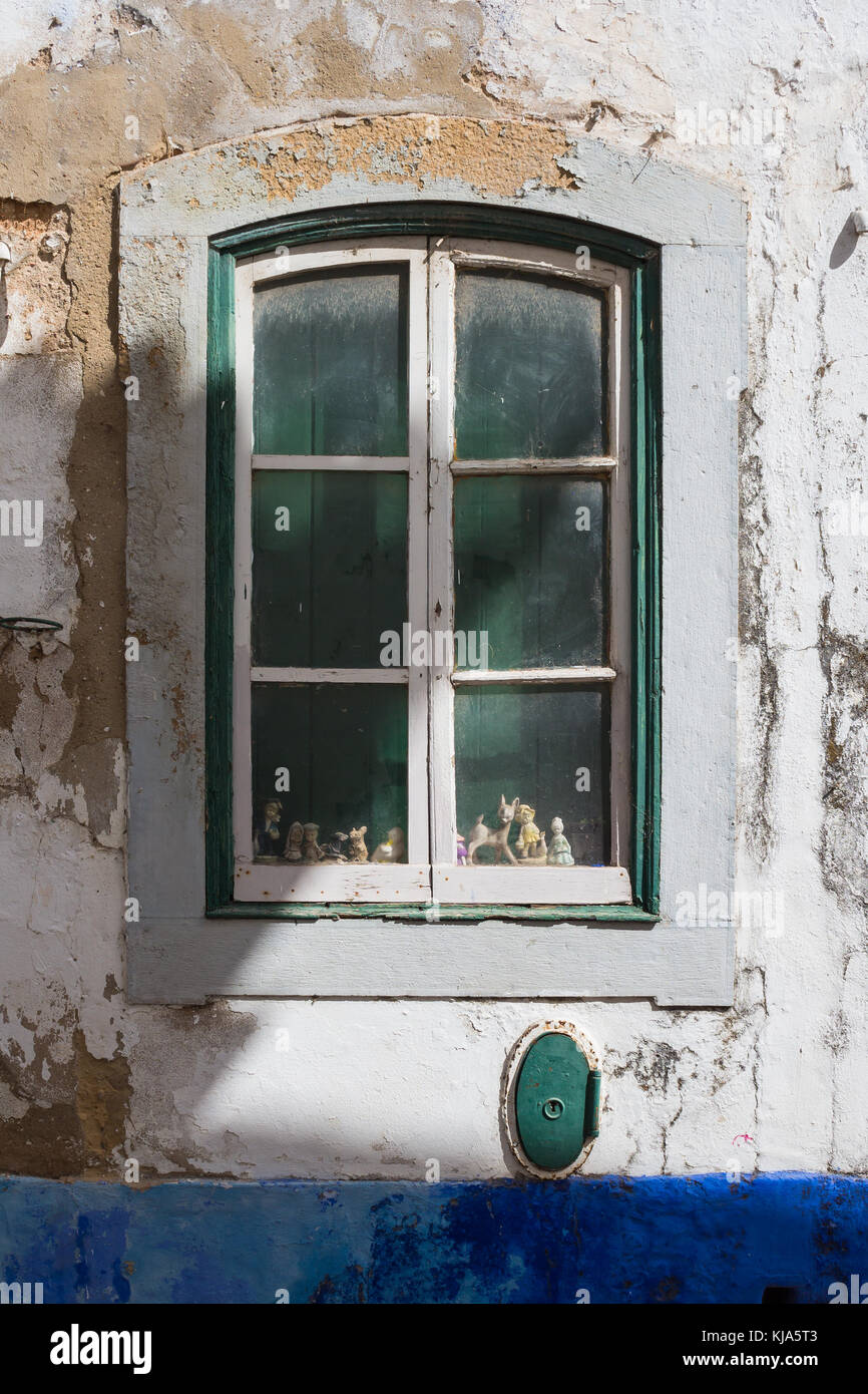 Closed old dusty window with a green inner shutter and little toys in ...