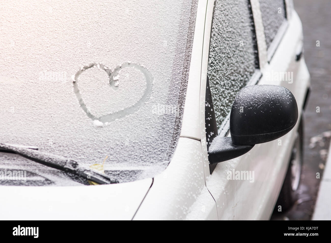 Shape of heart drawn on snow on front window of the car. First snow ...