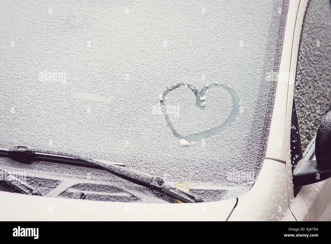 Shape of heart drawn on snow on front window of the car. First snow ...