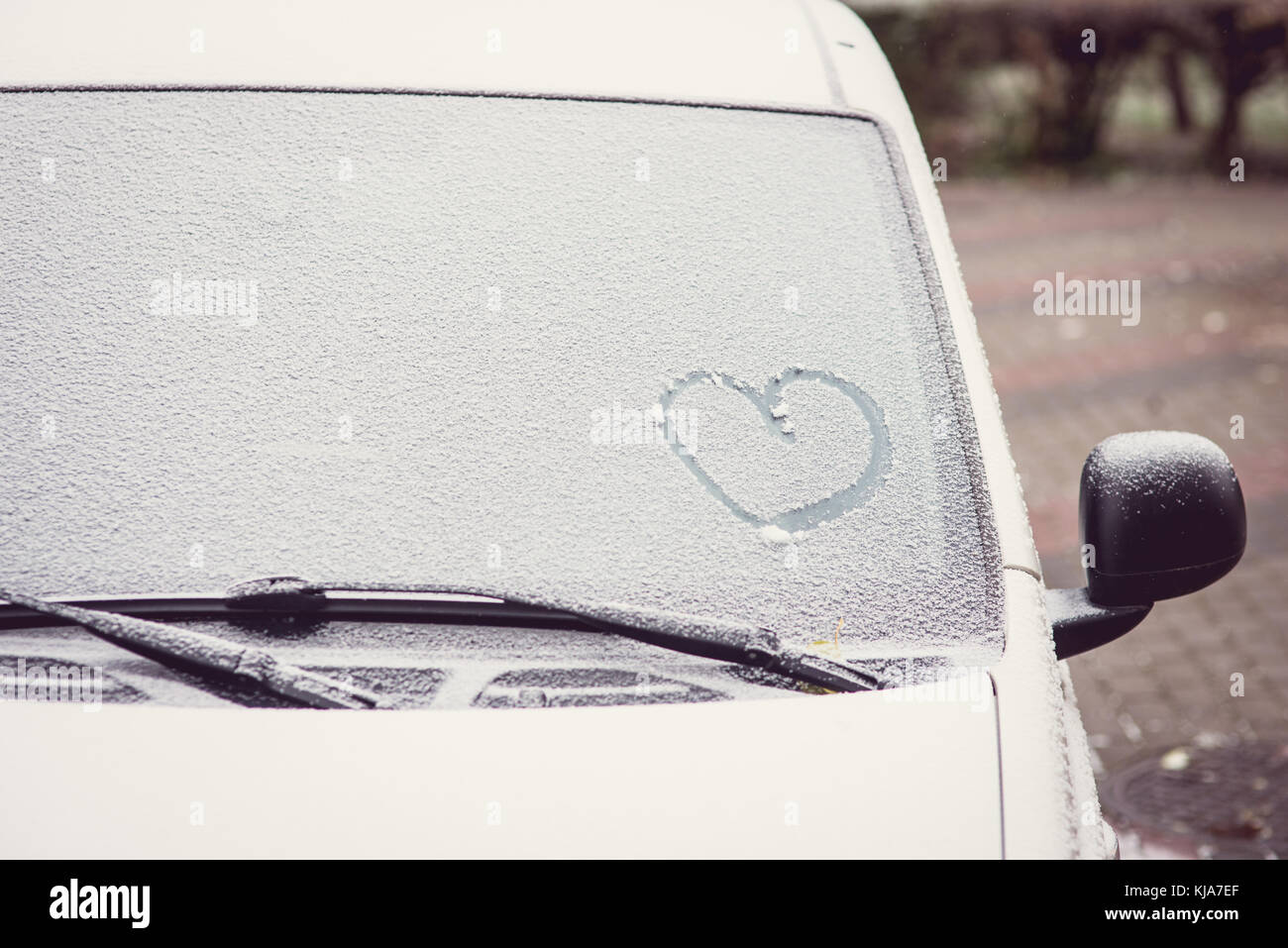 Shape of heart drawn on snow on front window of the car. First snow ...