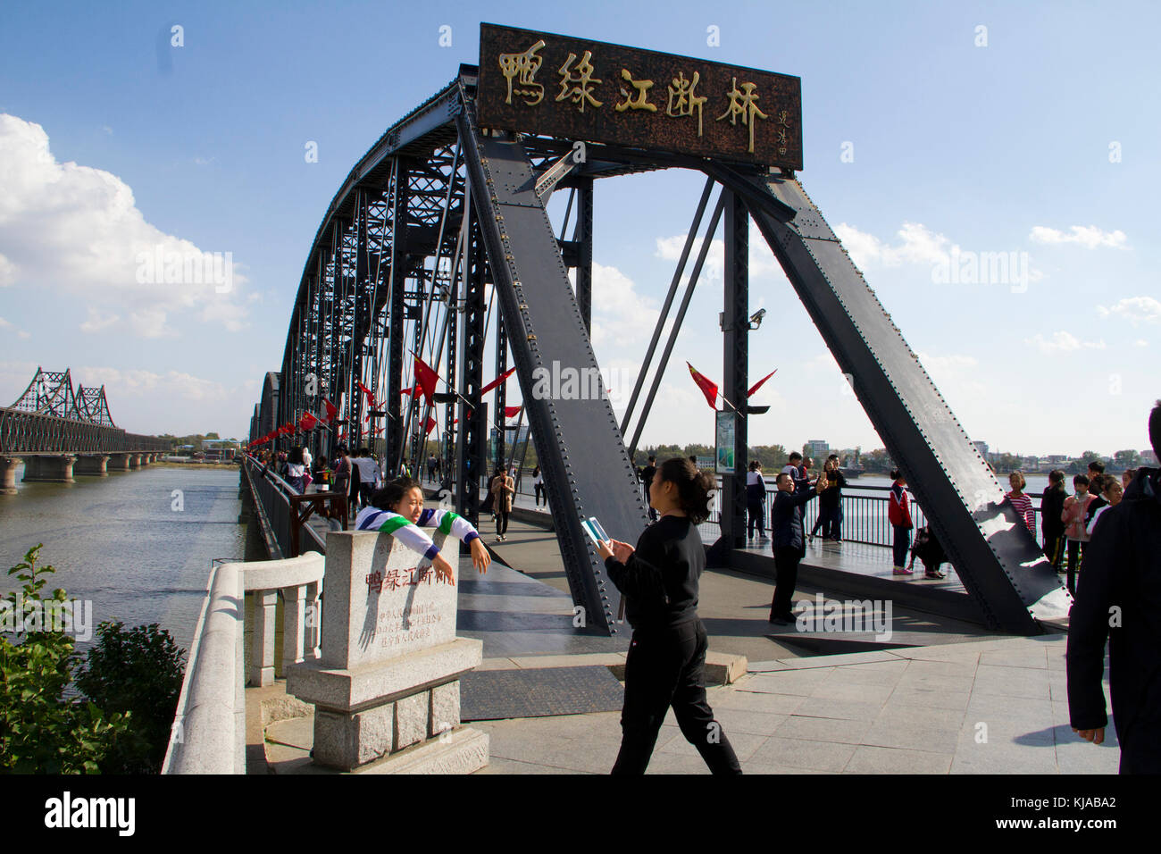 Tourists walk across the Broken Bridge on the Yalu river in Dandong ...