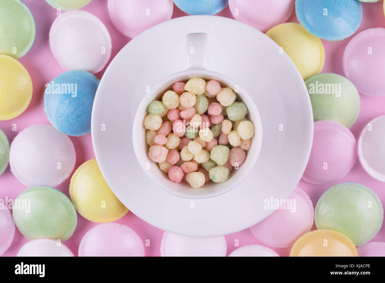 Small pastel color sweeties in a white cup on pink table Stock Photo ...