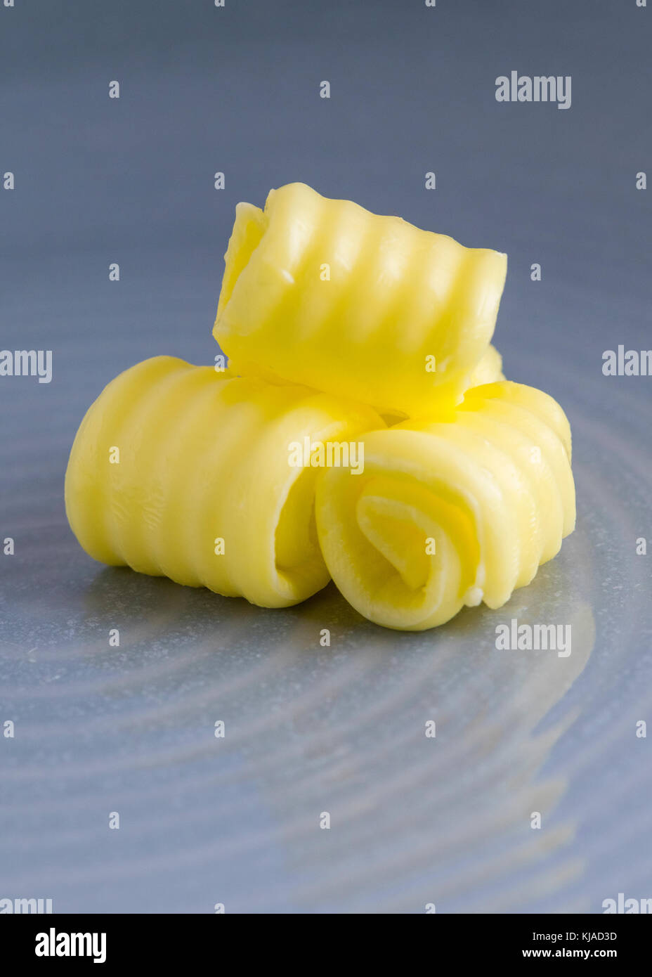 vertical image of fresh organic butter curled on a plate with space for ...