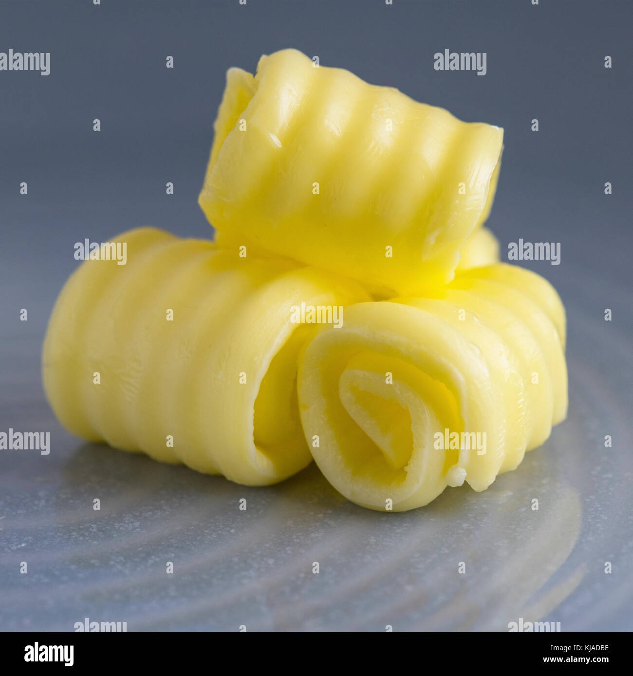 square format of fresh organic butter curled on a plate with space for ...