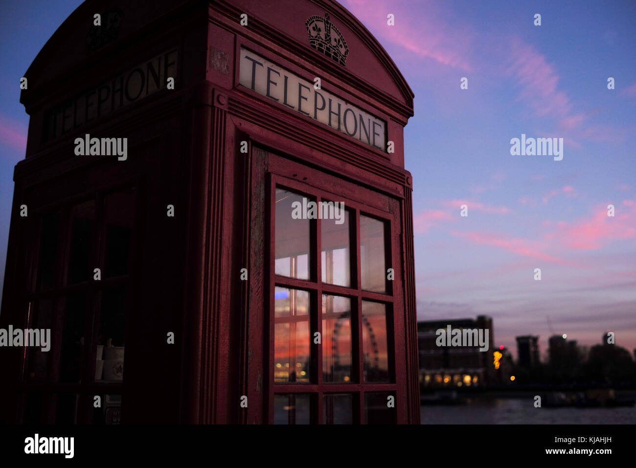 Traditional English telephone red box in London with sunset reflected ...