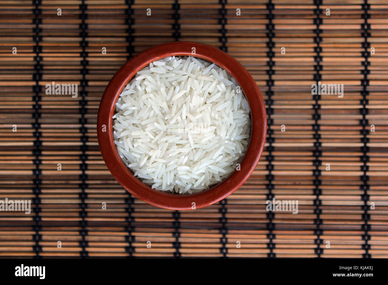 Bowl filled with white raw basmati rice grains with bamboo background ...