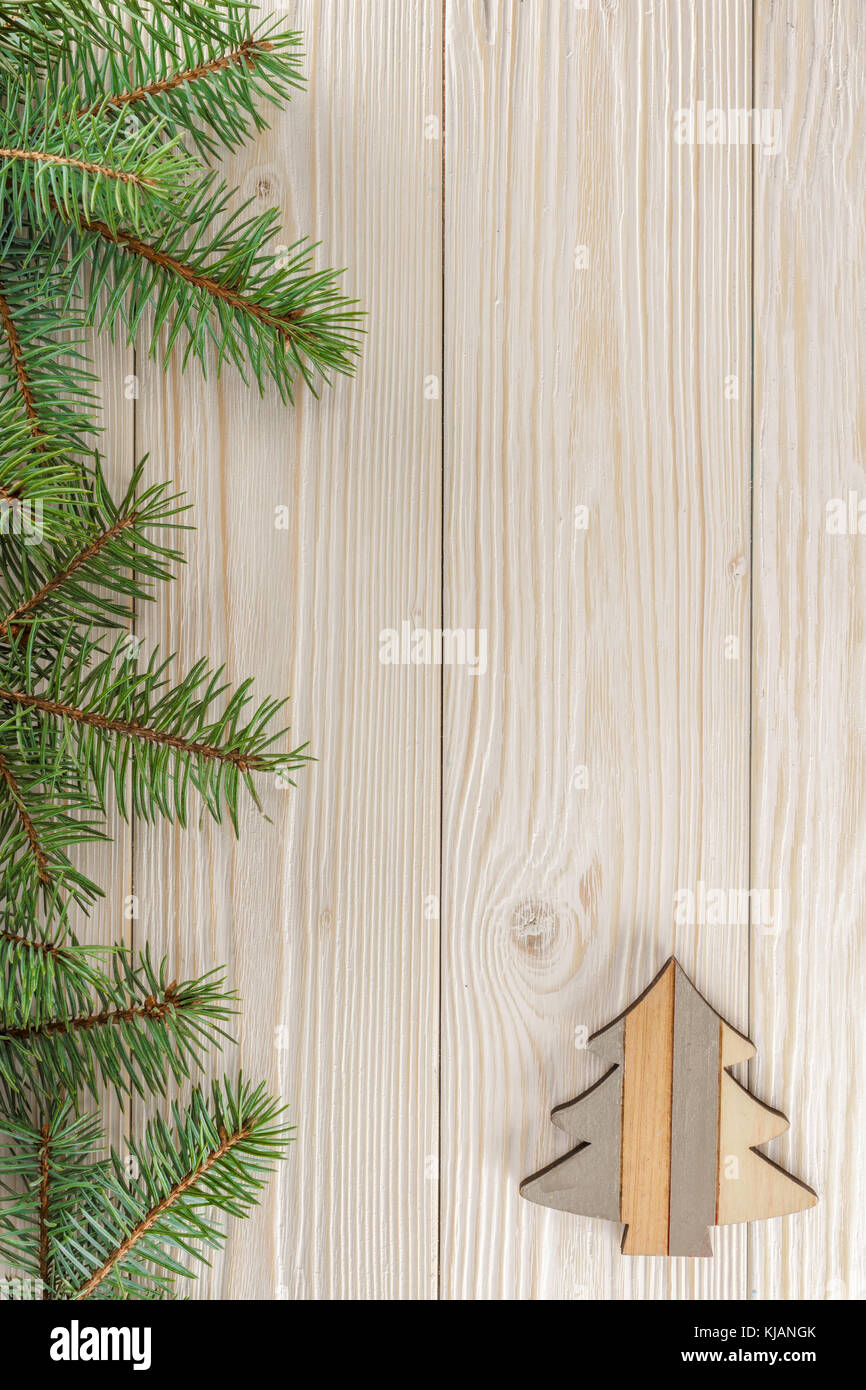 A small Christmas tree on white wooden background. The frame of spruce ...
