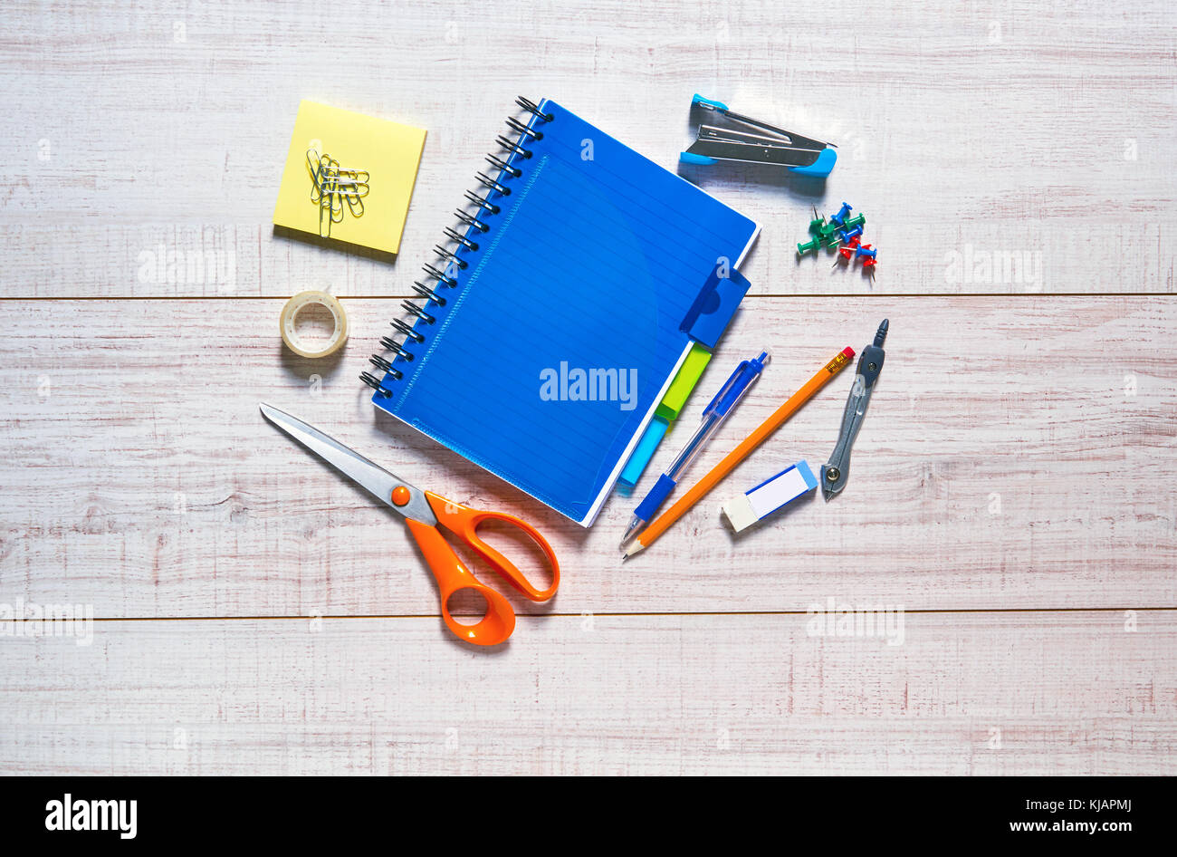 View of a wooden table with a notebook, pen, pencil, rubber, scissors ...