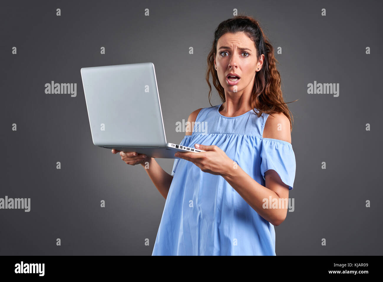 A beautiful young woman standing and felling surprised while grabbing a ...