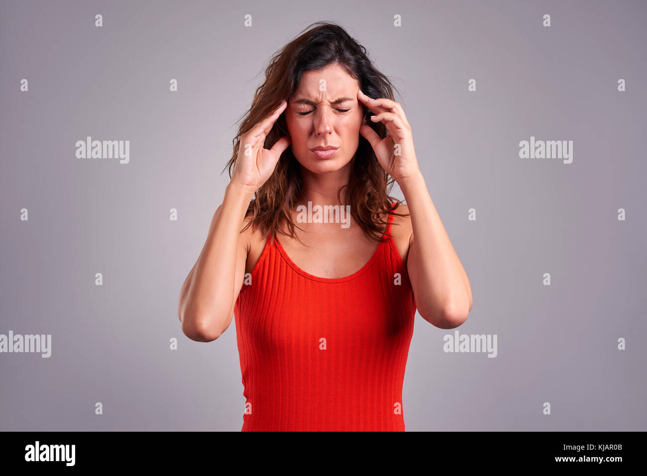 A beautiful young woman having a headache and grabbing her head in a ...