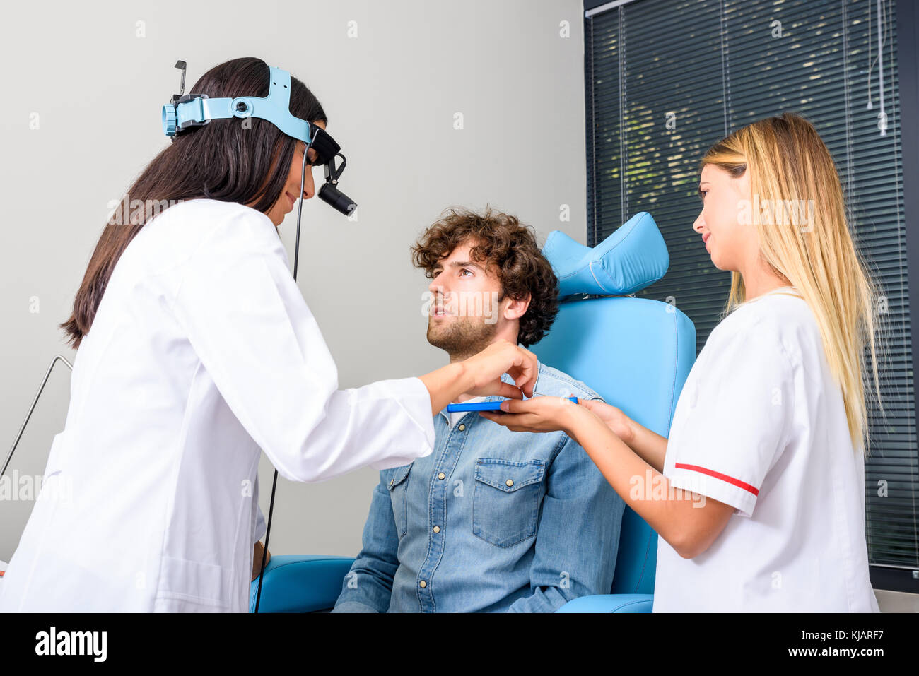 A female Ear-Nose-Throat aka ENT specialist doctor diagnosing a young ...