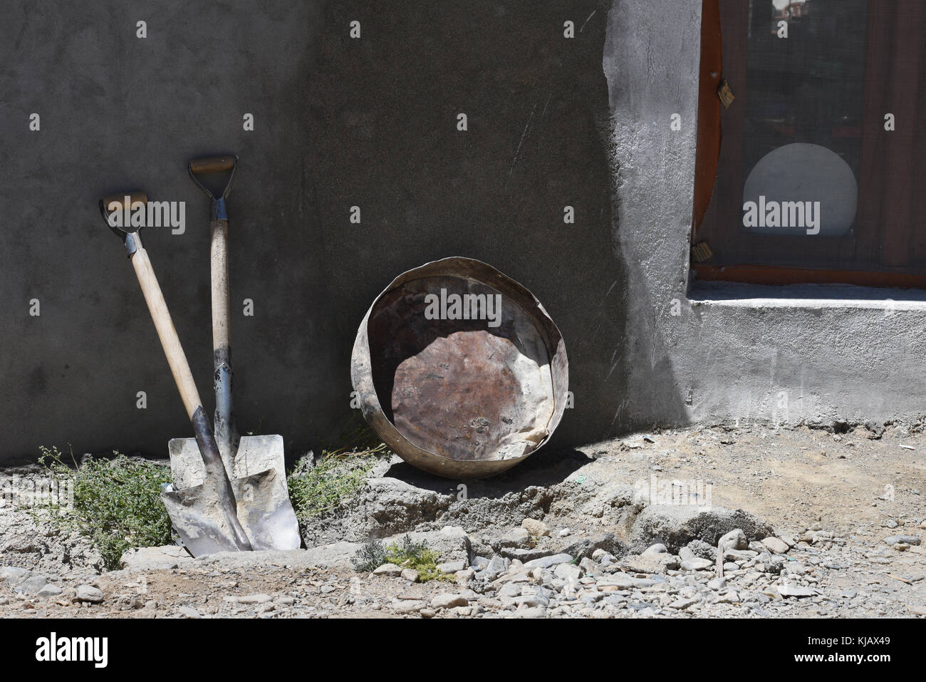 Two dirty big spades, a gray round bowl leaned against the clay wall of ...