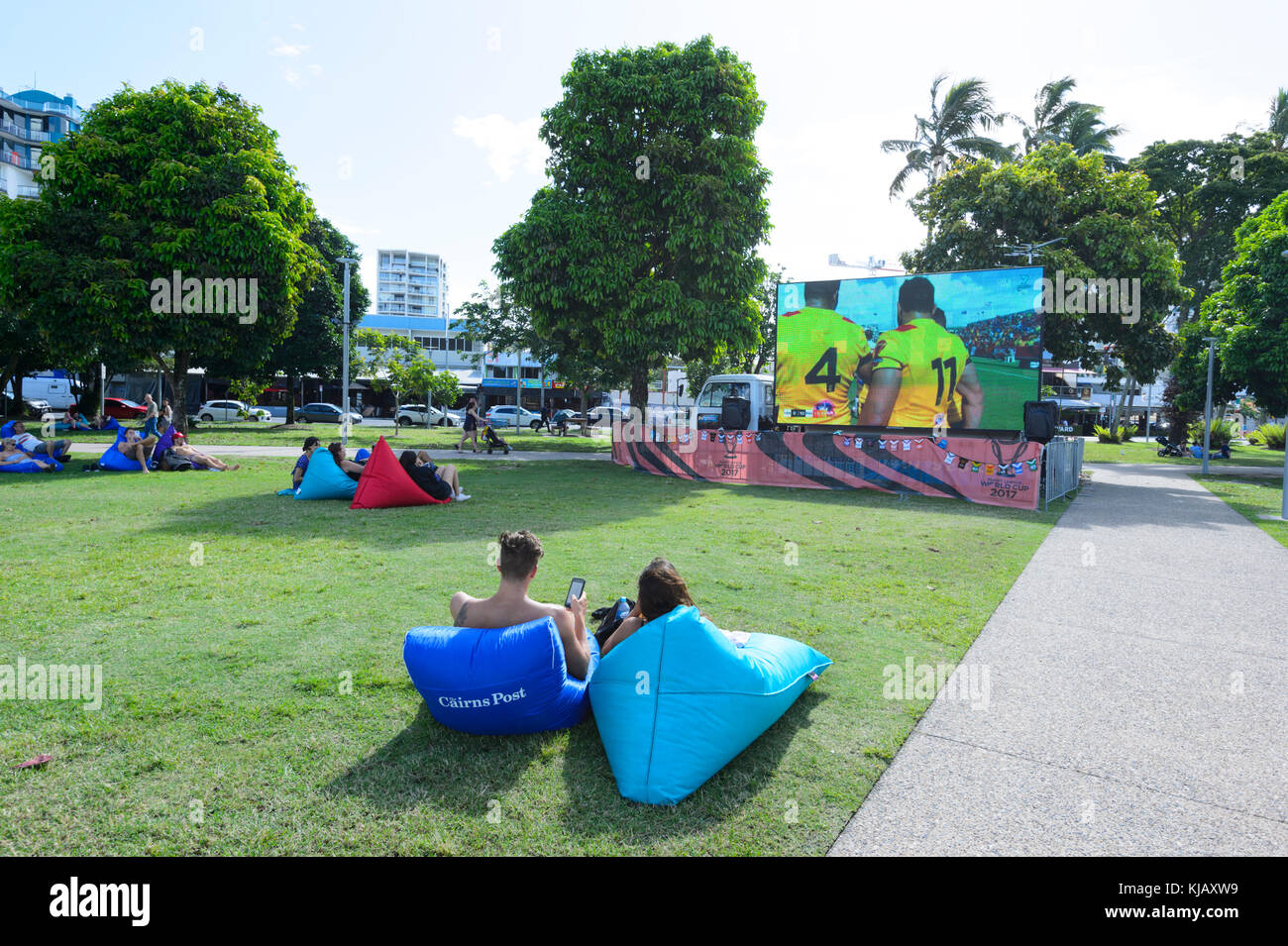 People leisurely watching a rugby match on a giant TV screen from their ...