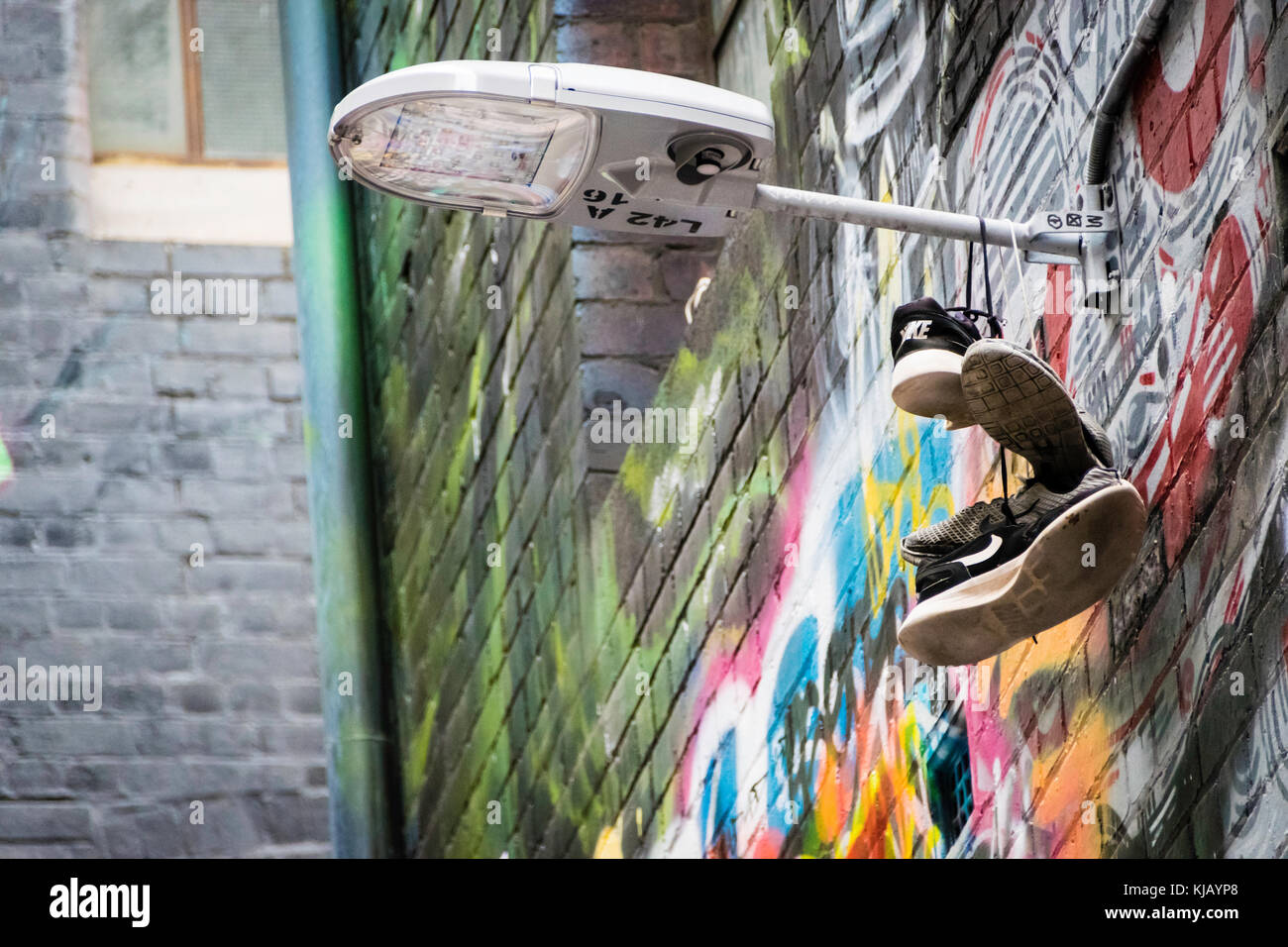 Sneakers hanging from a lamp post in a graffiti covered alleyway Stock ...