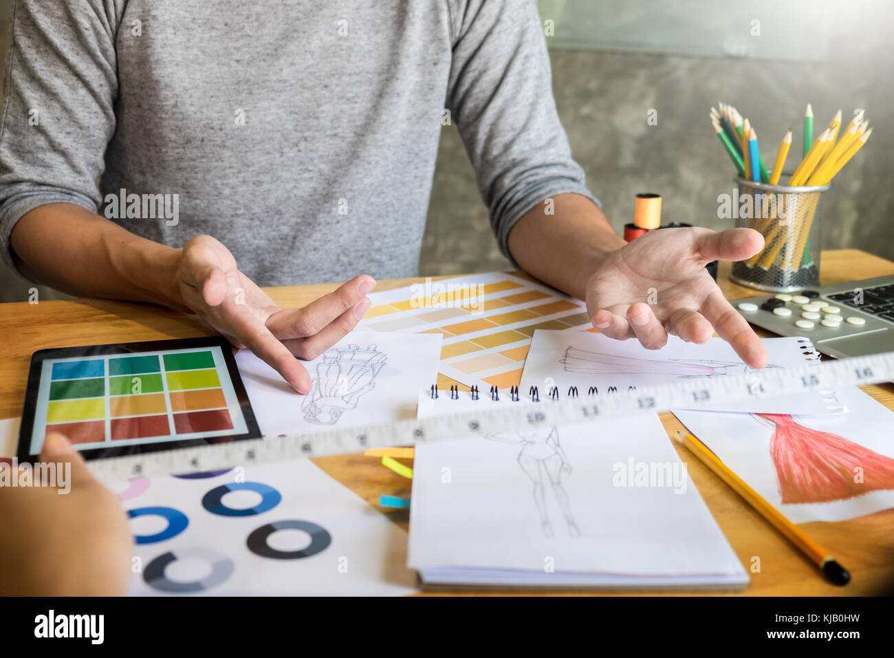 two young women working as fashion designers and drawing sketches and ...