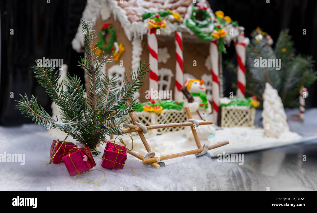 Sprig of Christmas tree with small gifts near gingerbread house on dark ...