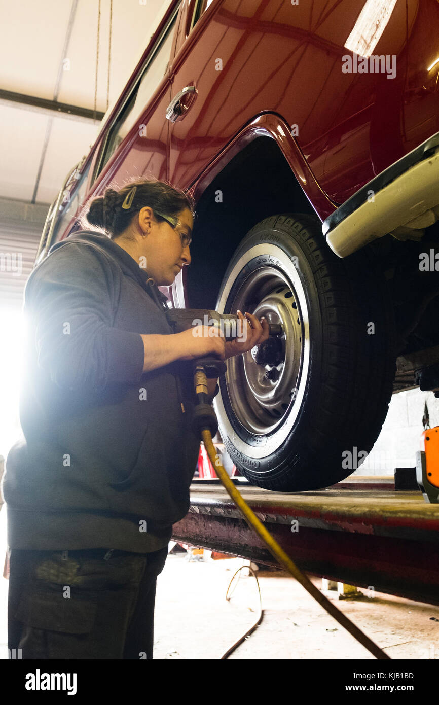 A female mechanic working in a small independent garage workshop ...