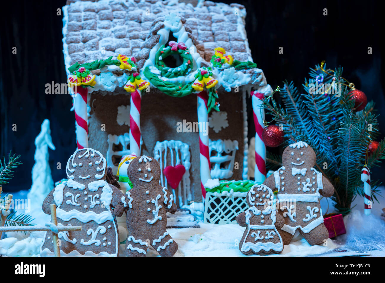 Sweet gingerbread family near snow-covered homemade gingerbread house ...