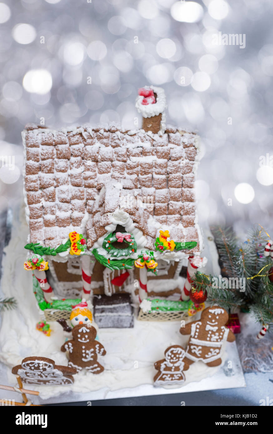 Snow-covered roof of homemade gingerbread house with protruding legs of ...