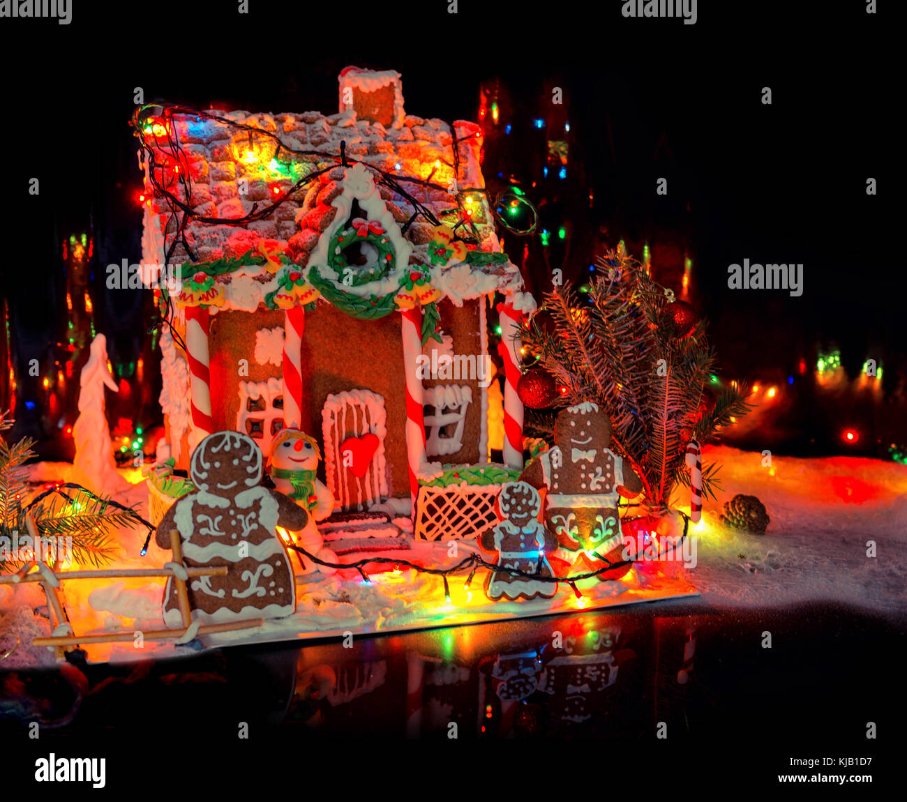 Adorable gingerbread family near big snow-covered homemade gingerbread ...