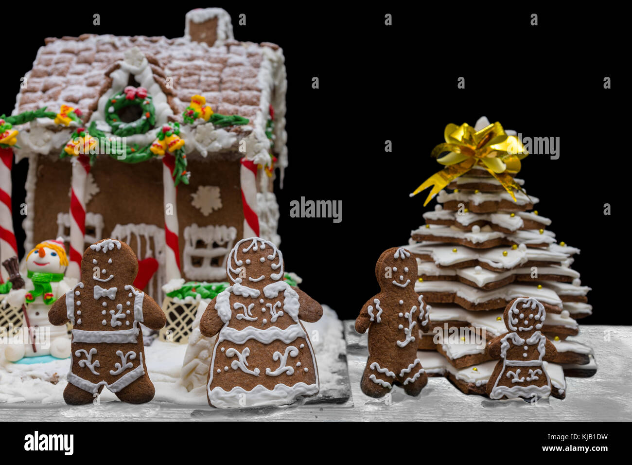 Cute gingerbread family near snow-covered homemade gingerbread house ...