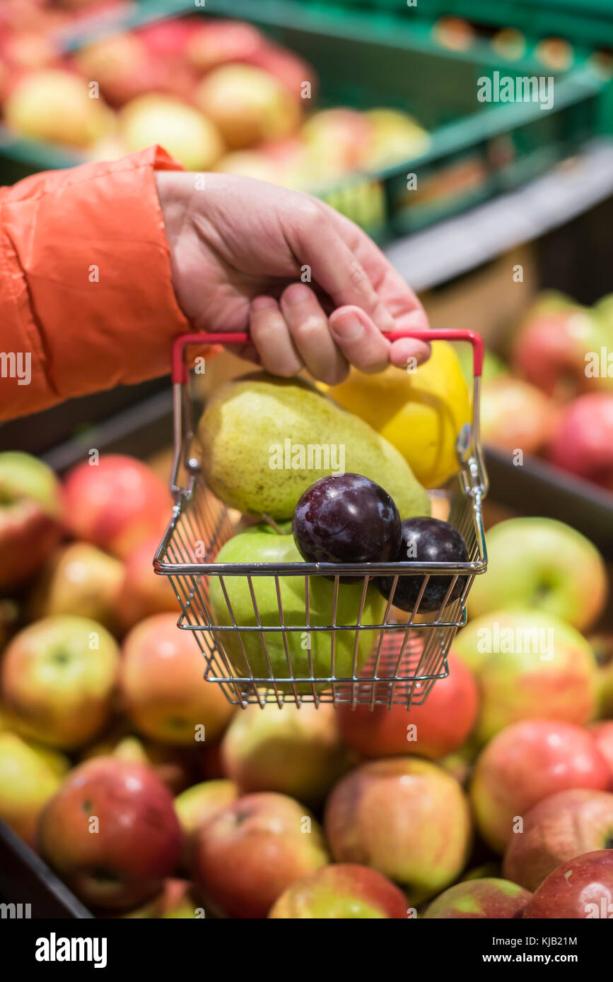 Fruits in supermarket. Buying apples and pears in shop. Small basket ...