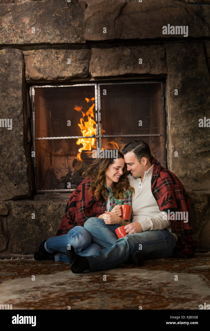 Smiling Caucasian couple cuddling on floor near fireplace Stock Photo ...