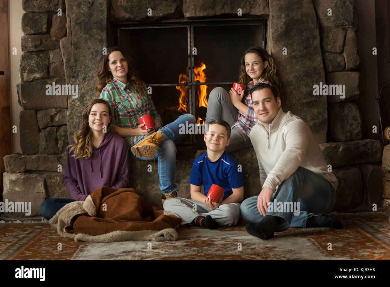 Smiling Caucasian family sitting near fireplace Stock Photo - Alamy