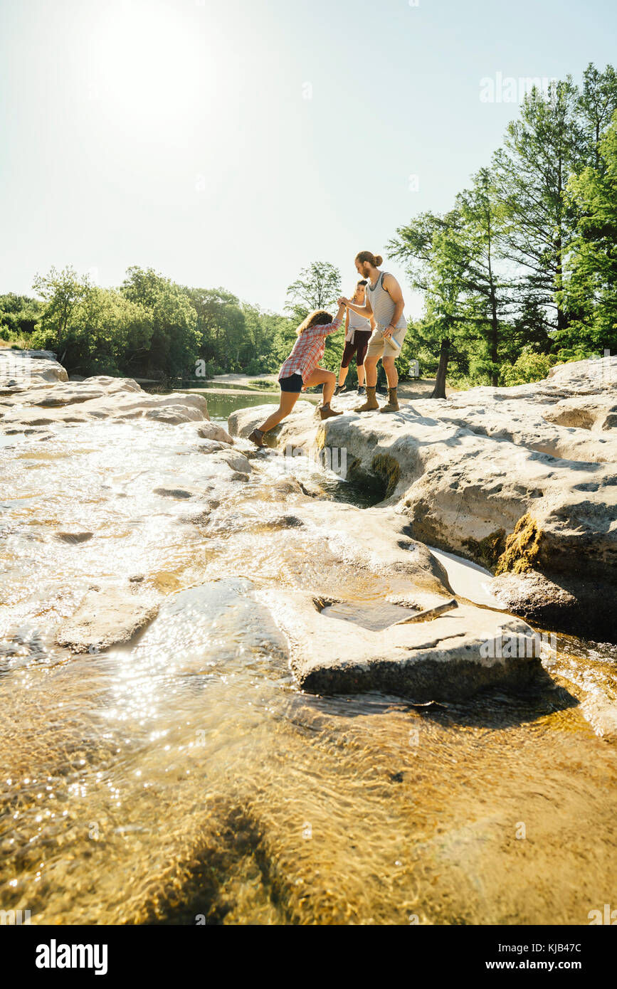 Man helping woman crossing river Stock Photo - Alamy