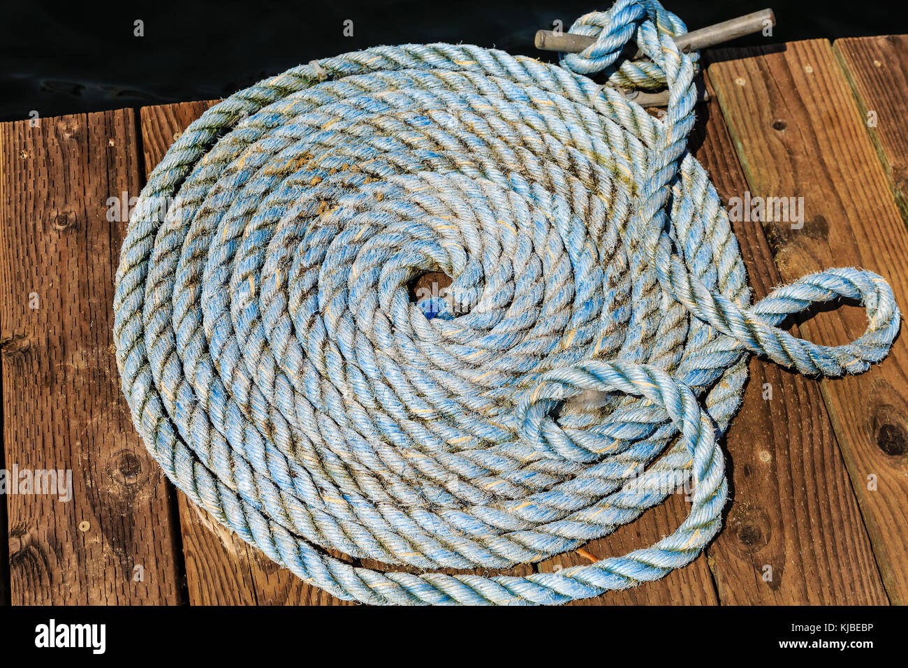 Rope Coiled and Ready on a wood dock Stock Photo - Alamy