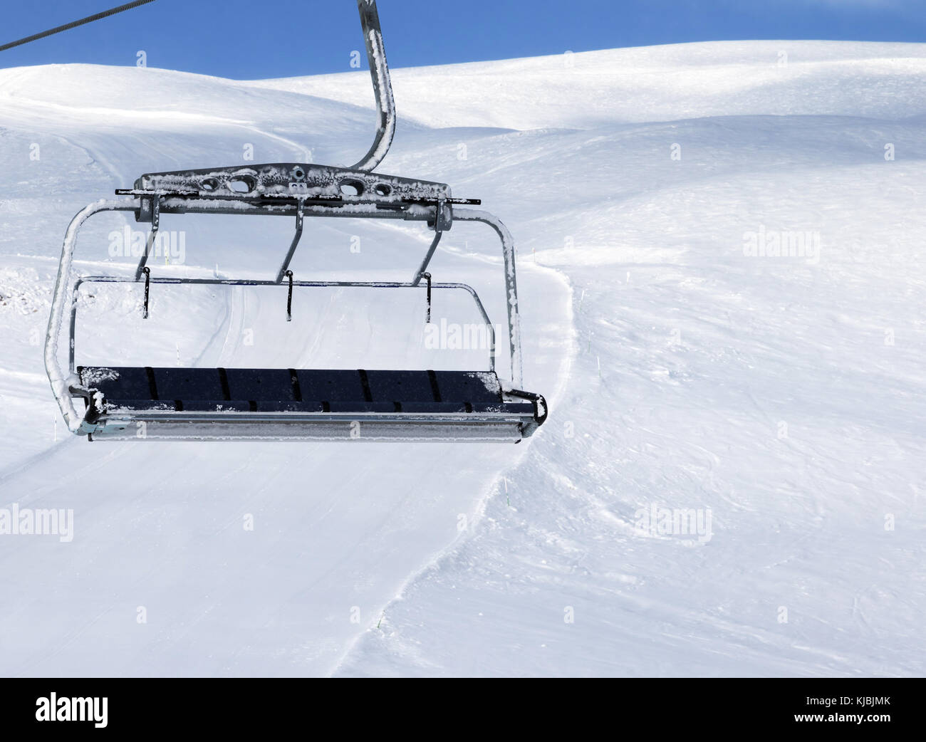 Ski slope, chair-lift with falling snow on ski resort and blue sky at ...