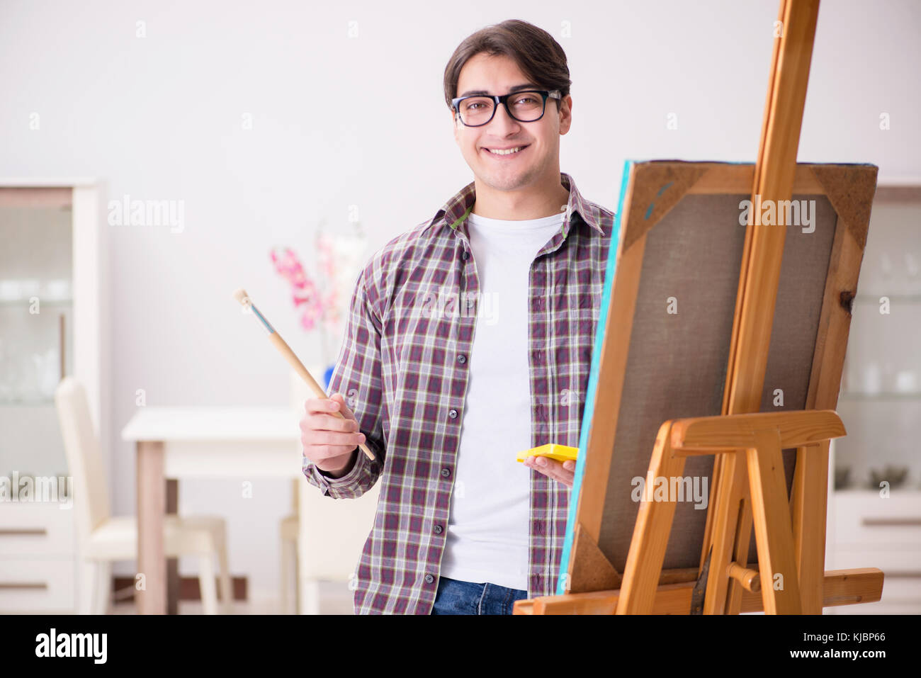 Young male artist drawing pictures in bright studio Stock Photo - Alamy