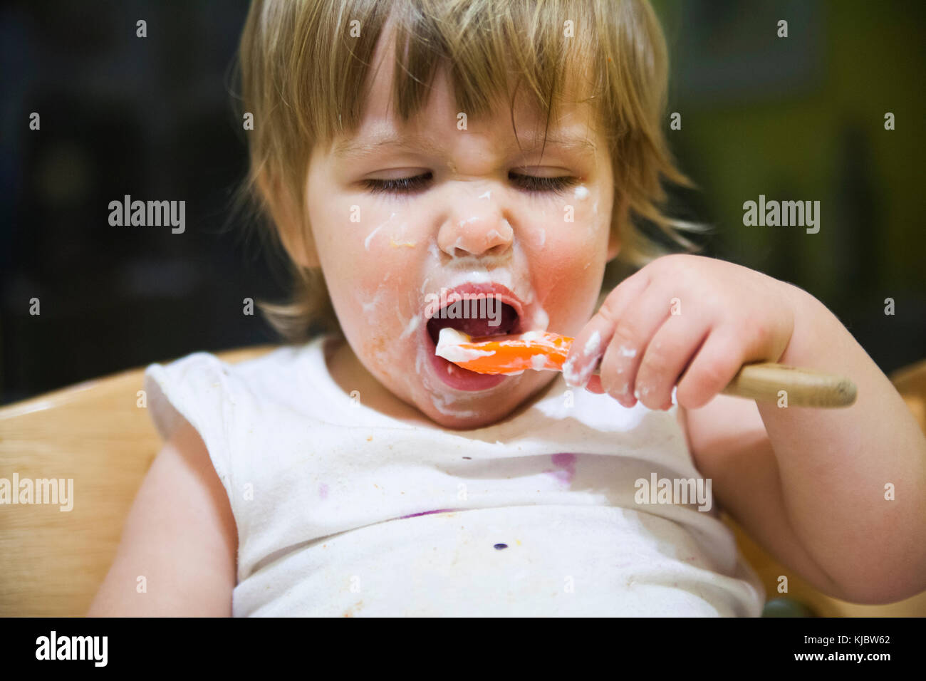 Messy child eating with a spoon Stock Photo - Alamy