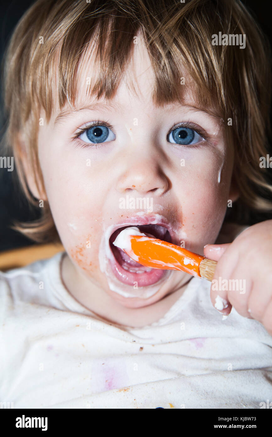 Messy child eating with a spoon Stock Photo - Alamy