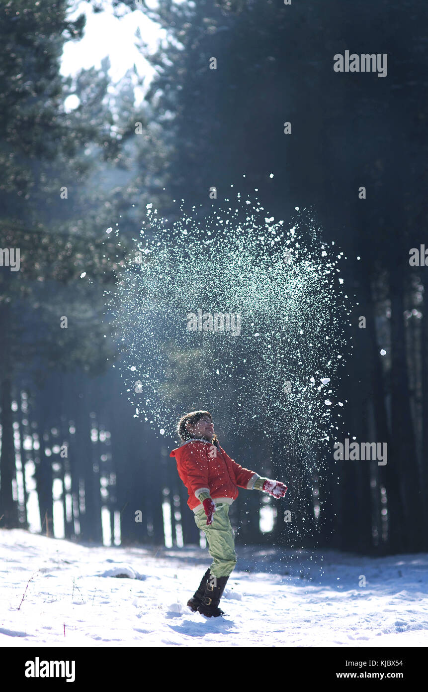 Young girl throwing snow in the air, having fun. Winter scene in the ...