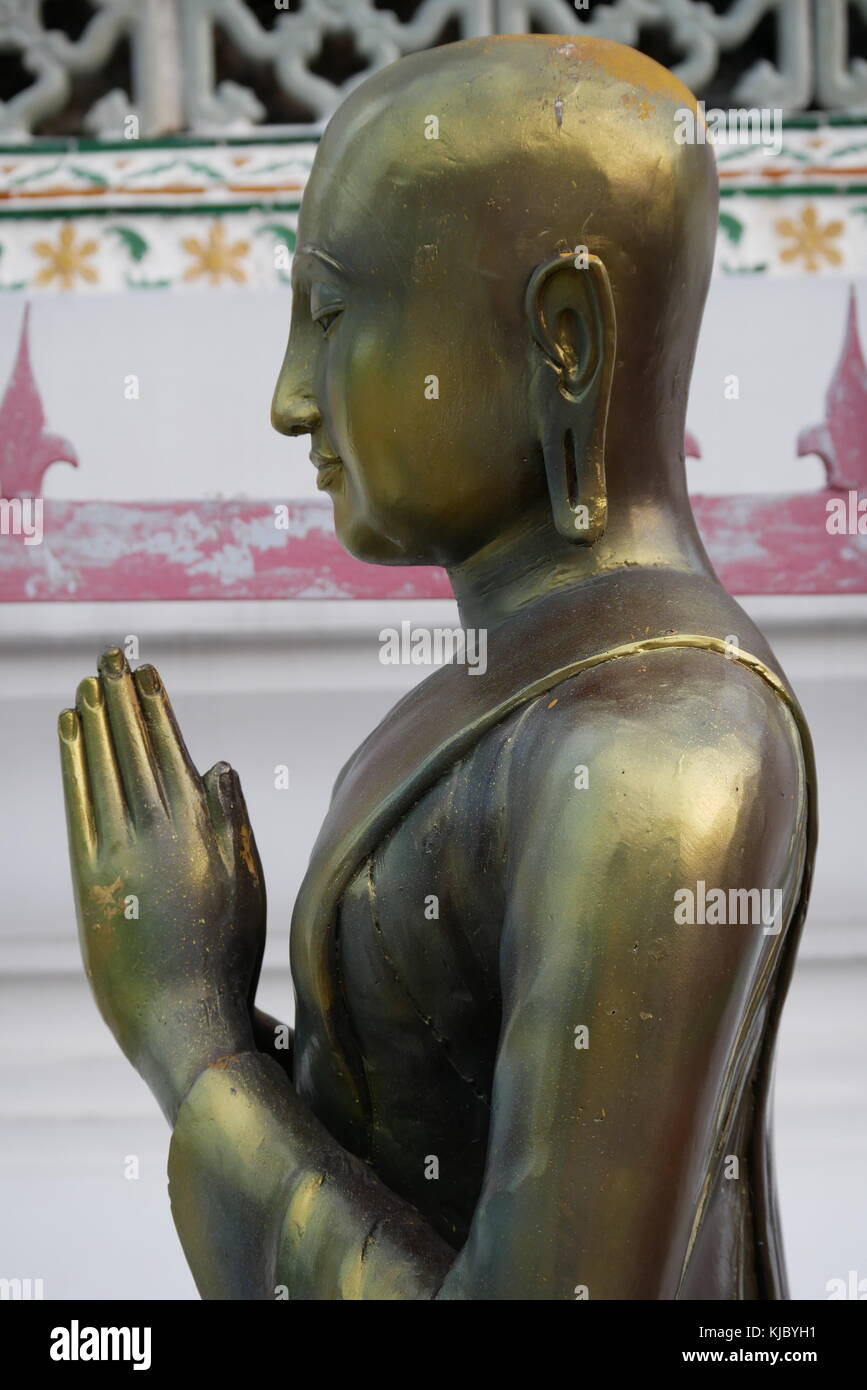 A side-profile picture of a statue of a golden Buddha praying in Wat ...