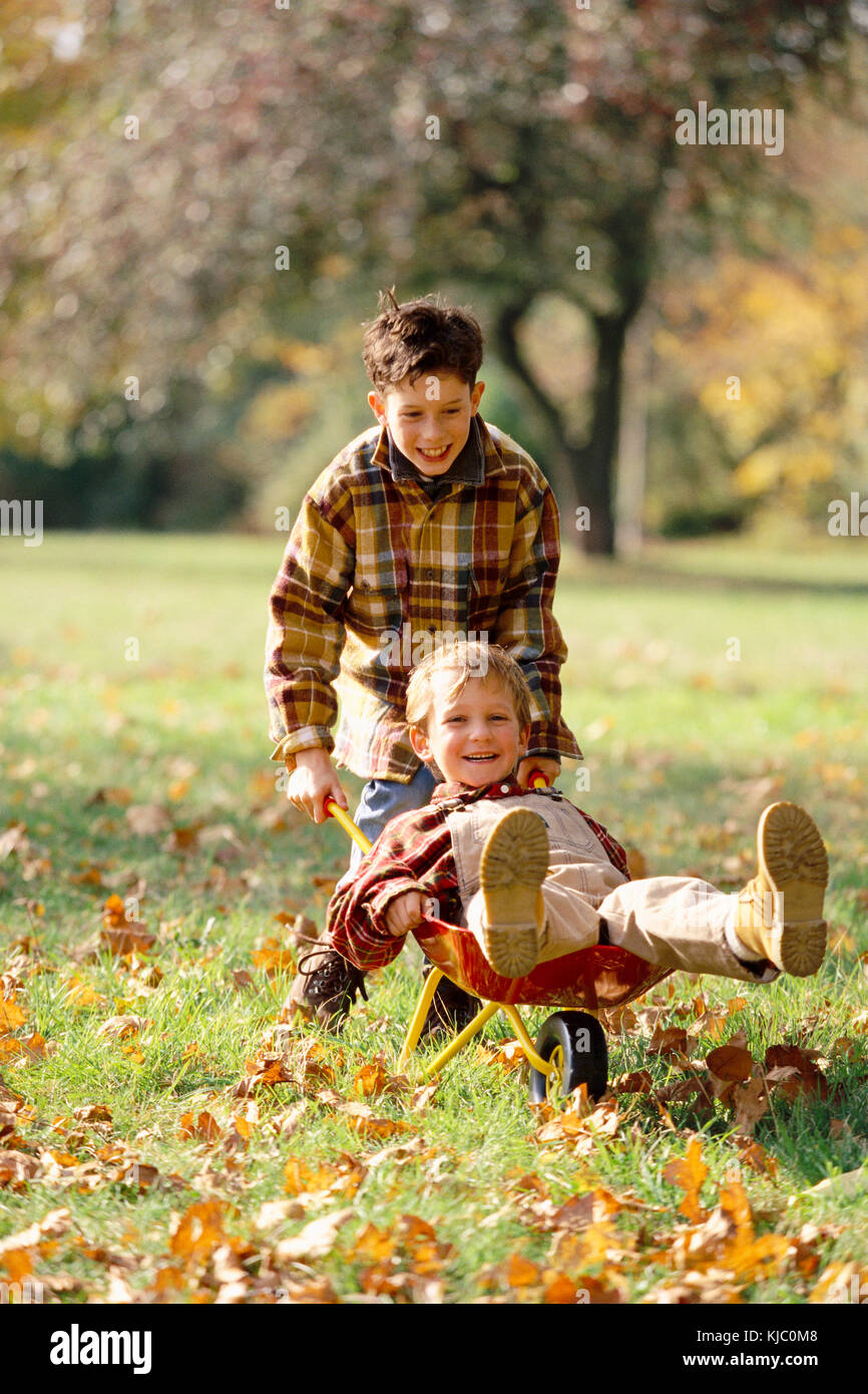 Boy Pushing Boy in Wheelbarrow Stock Photo - Alamy