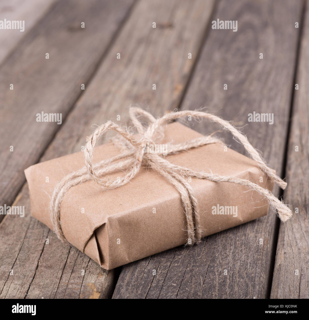 Present wrapped in brown paper and tied with string on a wood surface ...