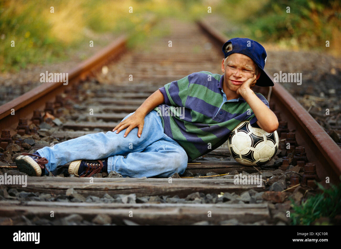 Boy With Soccer Ball Lying Down In Train Tracks Stock Photo - Alamy