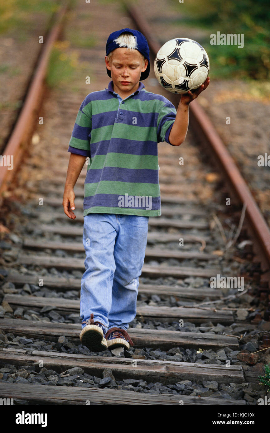Boy With Soccer Ball Walking Along Train Tracks Stock Photo - Alamy