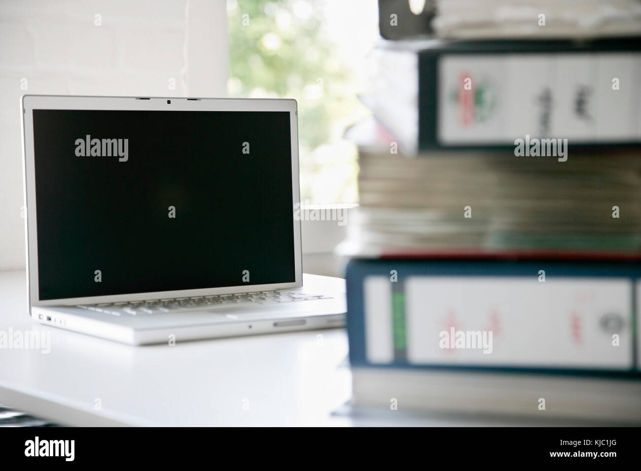 Stacked Binders and Laptop Computer on Office Desk Stock Photo - Alamy