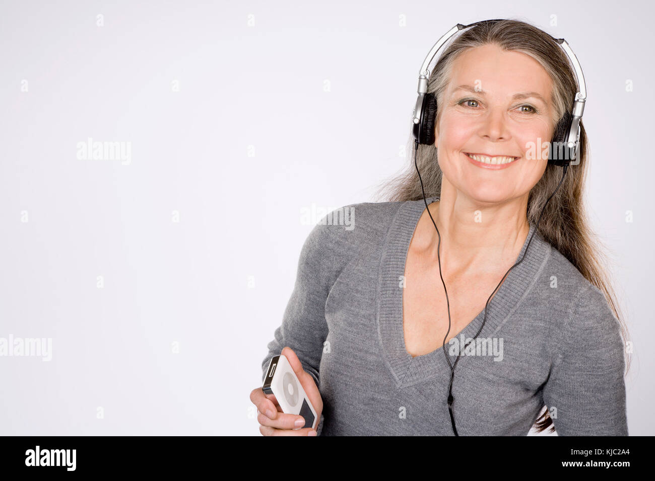 Mature Woman Listening to MP3 Player Stock Photo - Alamy
