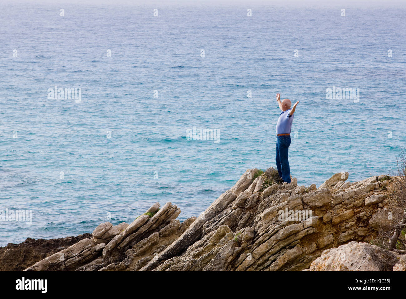 Man Standing on Cliff Looking Out at Ocean Stock Photo - Alamy